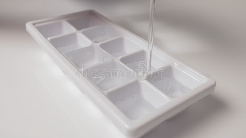 Making Ice for Beverages. Pouring Water in Container for Preparing Ice ...