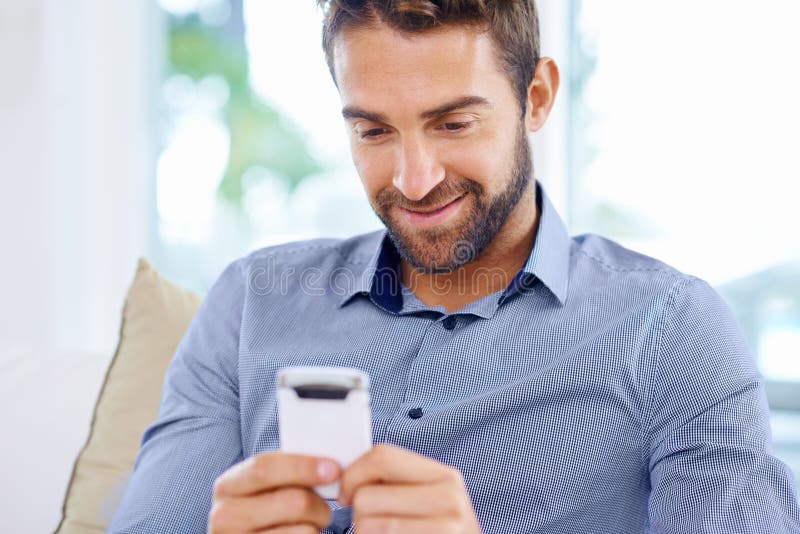 Making the Most of His Apps. Man Using His Cell Phone in His Lounge ...