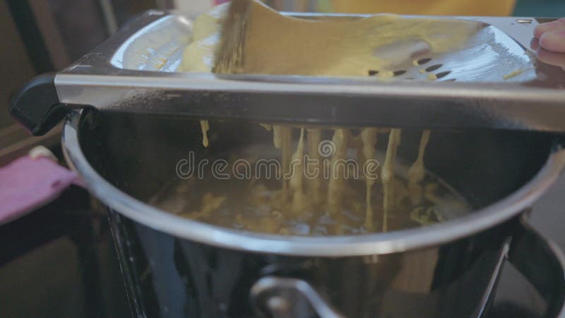 Making Spaetzle by Scraping or Grating Dough into Big Pot with Boiling ...