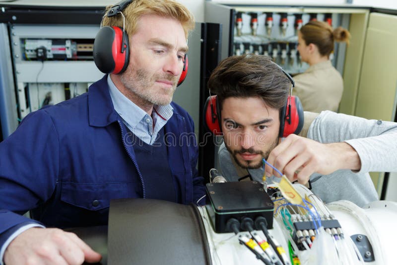Male Apprentice Technician Working Under Supervision Stock Photo ...