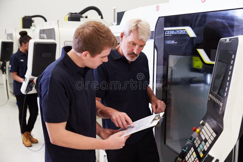 Male Apprentice Working with Engineer on CNC Machinery Stock Photo ...
