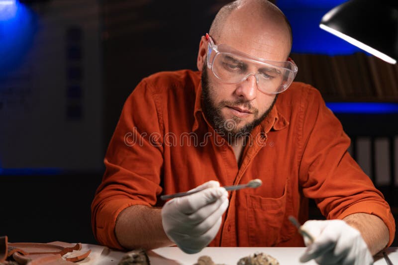 Male Archaeologist Working in the Office at Night Studying Artifacts ...