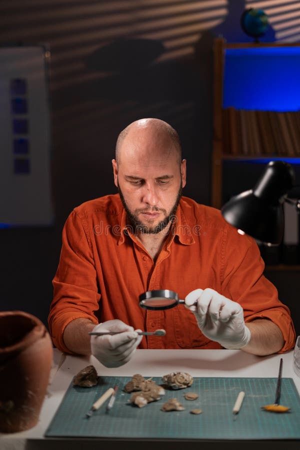 Male Archaeologist Working in the Office at Night Studying Artifacts ...