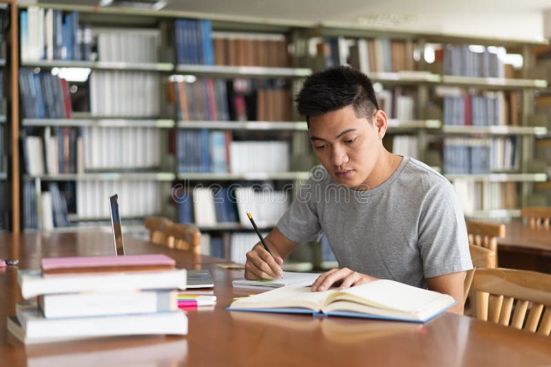 Male Asian Student Studying and Reading Book in Library Stock Photo ...