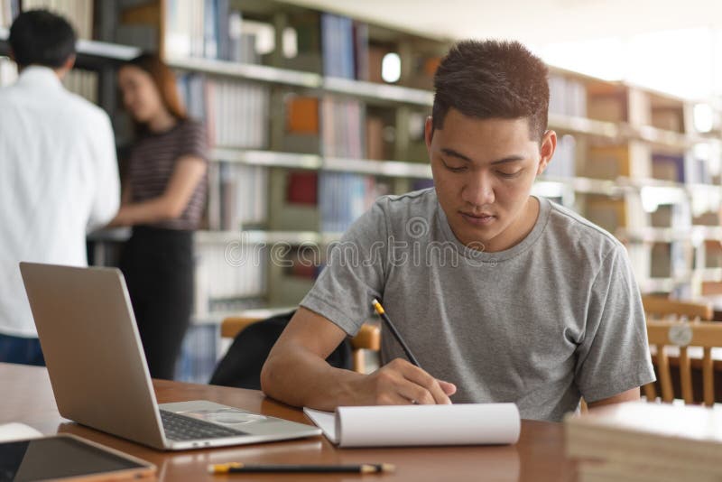 Male Asian Student Studying and Reading Book in Library Stock Image ...