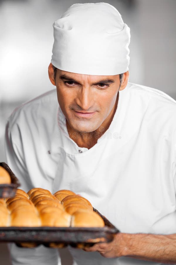 Male Baker Looking at Freshly Baked Breads in Baking Tray Stock Photo ...
