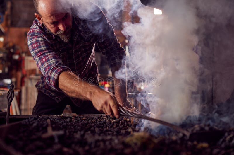 Male Blacksmith Raking Coals Fuel To Start Blaze in Forge Stock Photo ...