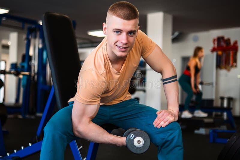 A Male Bodybuilder Trains with Dumbbells in a Gym. Stock Photo - Image ...