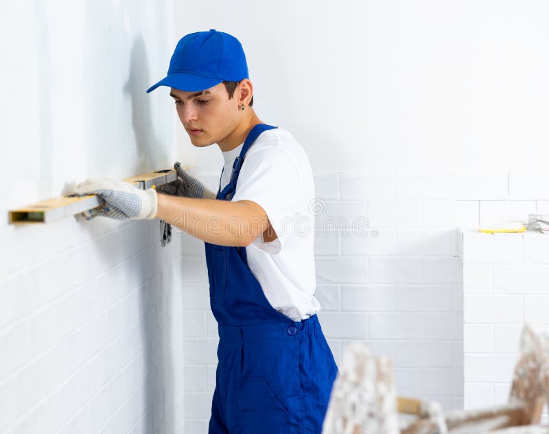 Male Builder in Blue Overalls Measures Deviations from a Given Vertical ...