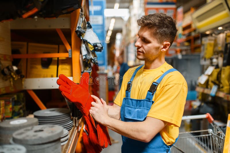 Male Builder Choosing Gloves in Hardware Store Stock Photo - Image of ...