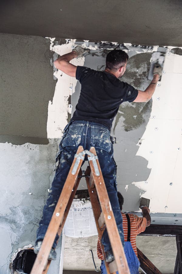 Male Builder at Work Overalls Plastering and Restoring Old Wall Using a Construction Trowel ...