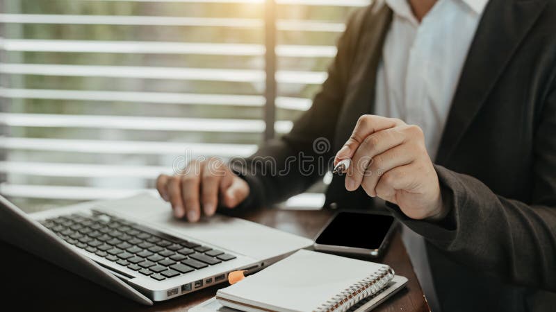 Male Businessman Use a Laptop Computer and Take Notes in the Notebook ...