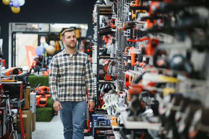 A Male Buyer Chooses Power Tools in a Hardware Store. a Large Selection ...