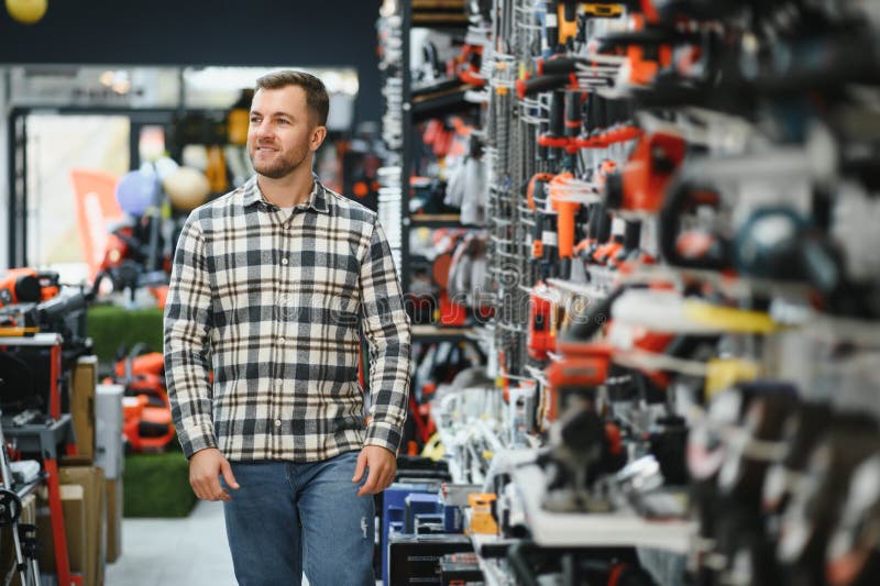 A Male Buyer Chooses Power Tools in a Hardware Store. a Large Selection ...