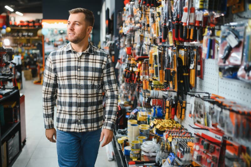 A Male Buyer in a Modern Hardware Store. a Large Selection of Tools and ...
