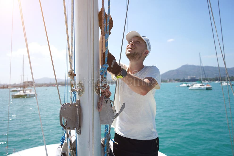 Male Captain on Deck of Sailboat Opening Sails Pulling the Rope Stock ...