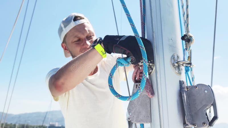 Male Captain on Deck of Sailboat Opening Sails Pulling the Rope Stock ...