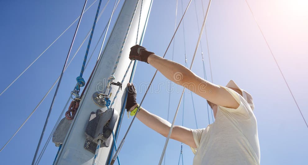 Male Captain on Deck of Sailboat Opening Sails Pulling the Rope Stock ...