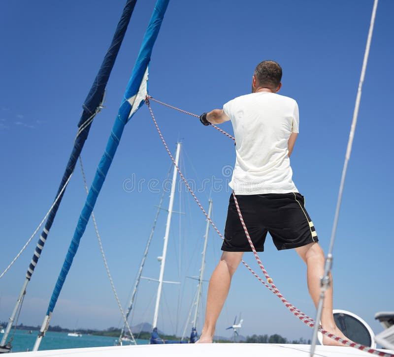 Male Captain on Deck of Sailboat Opening Sails Pulling the Rope Stock ...