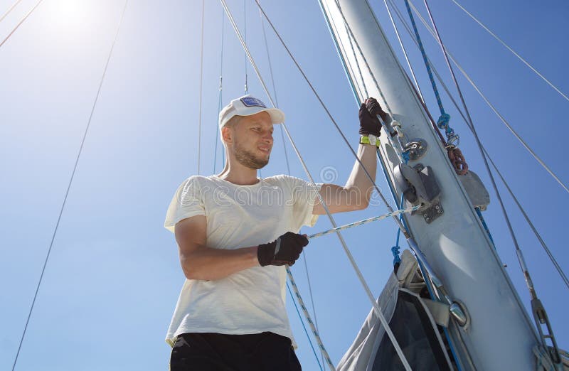 Male Captain on Deck of Sailboat Opening Sails Pulling the Rope Stock ...