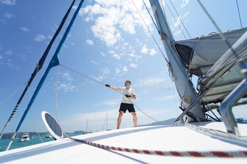 Male Captain on Deck of Sailboat Opening Sails Pulling the Rope Stock ...
