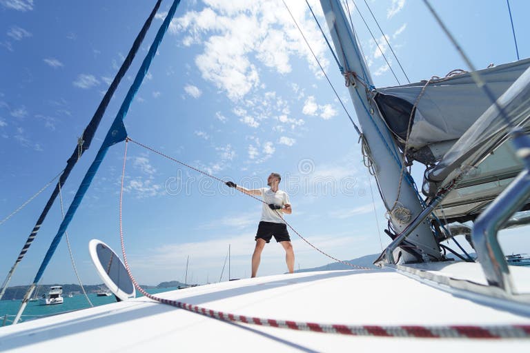 Male Captain on Deck of Sailboat Opening Sails Pulling the Rope Stock ...