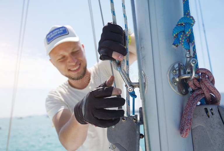 Male Captain on Deck of Sailboat Opening Sails Pulling the Rope Stock ...