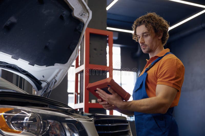 Male Car Technician Looking at Computer at Repair Service Station Stock ...