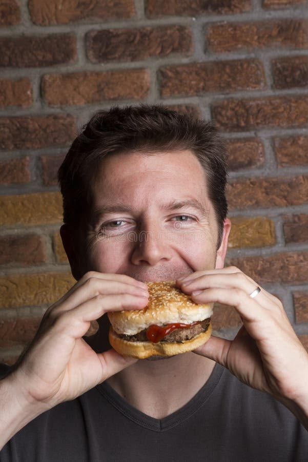 Male Carnivore Sinks Teeth into Burger Stock Image - Image of bite ...