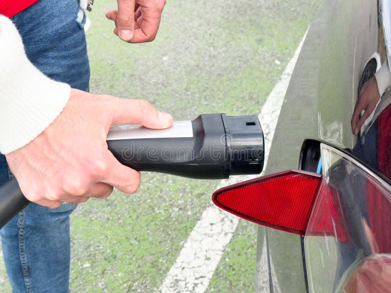 Male Charging Electric Car at Station with Focus on Plug and Tail Light ...