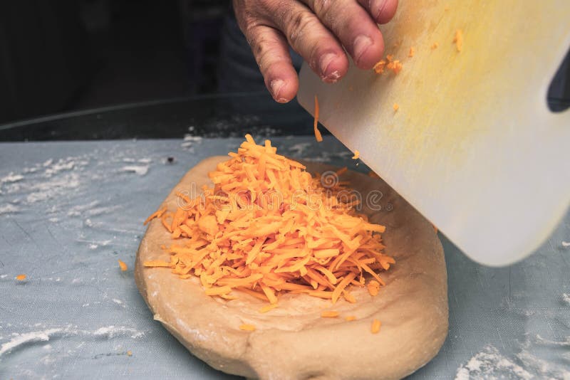 Male Chef Adding Shredded Red Cheddar Cheese on Top of Dough on a ...