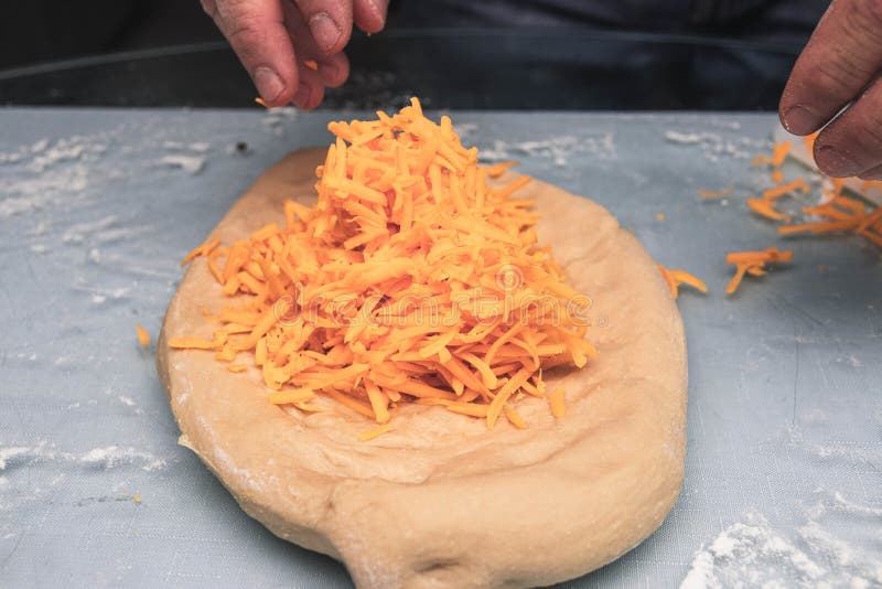 Male Chef Adding Shredded Red Cheddar Cheese on Top of Dough on a ...