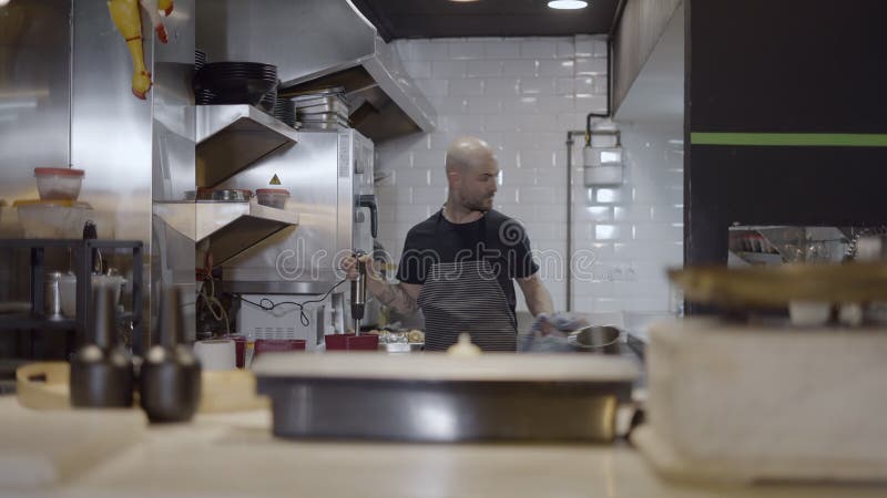 Male Chef Works in Restaurant Kitchen, Blurry Objects in Foreground ...