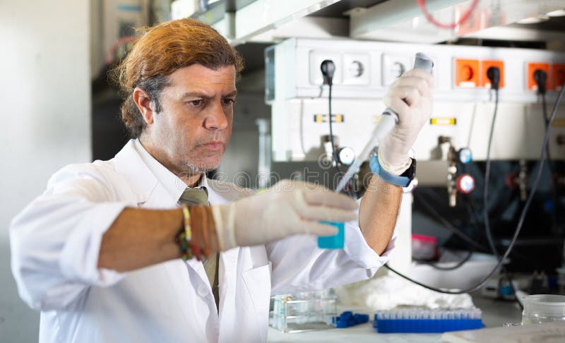Male Chemist Working in Laboratory, Analyzing Liquid Samples in Flasks ...