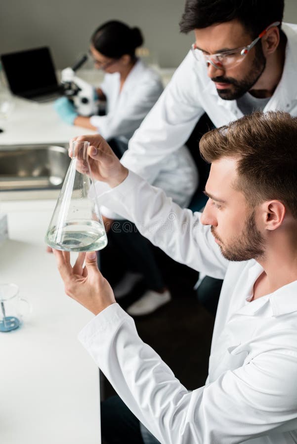 Male Chemists in Lab Coats Examining Reagent in Flask Stock Image ...