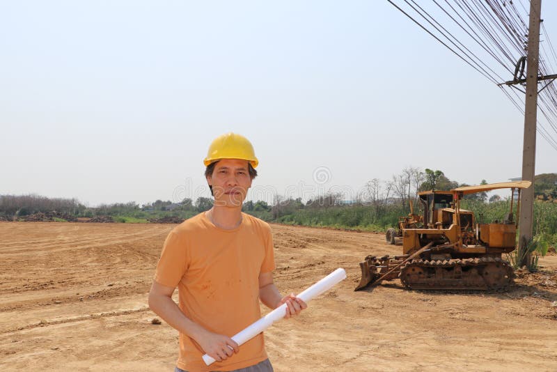 Male Civil Engineer Wear Yellow Helmet and Project Drafts while in Hand ...