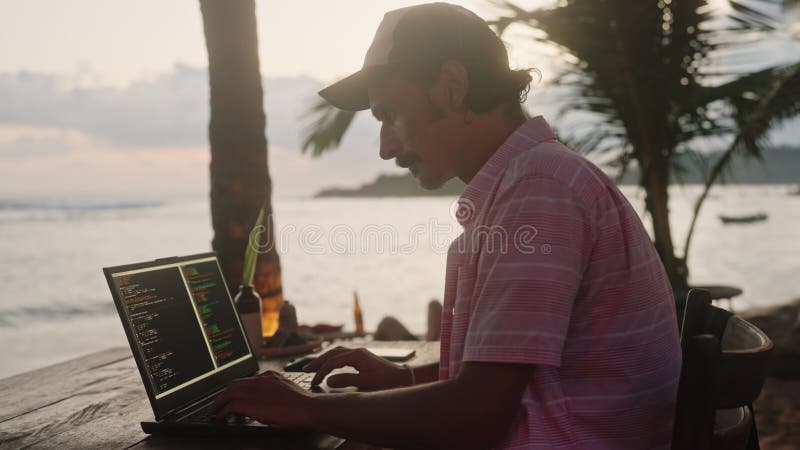 Software Developer Works On Laptop At Beach Cafe Programming With Sea