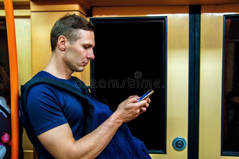 Male Commuter Reading from Mobile Phone Screen in Metro. Stock Image ...