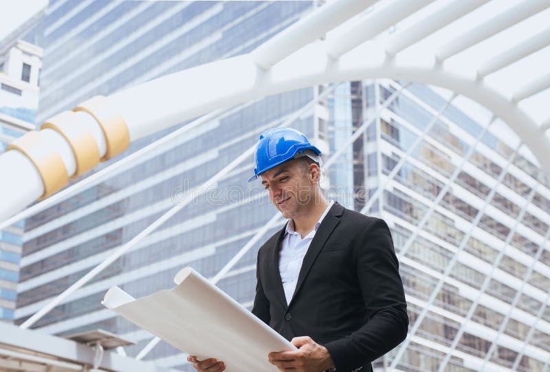 Male Construction Engineer Holding a Blueprints Reading Details of the ...