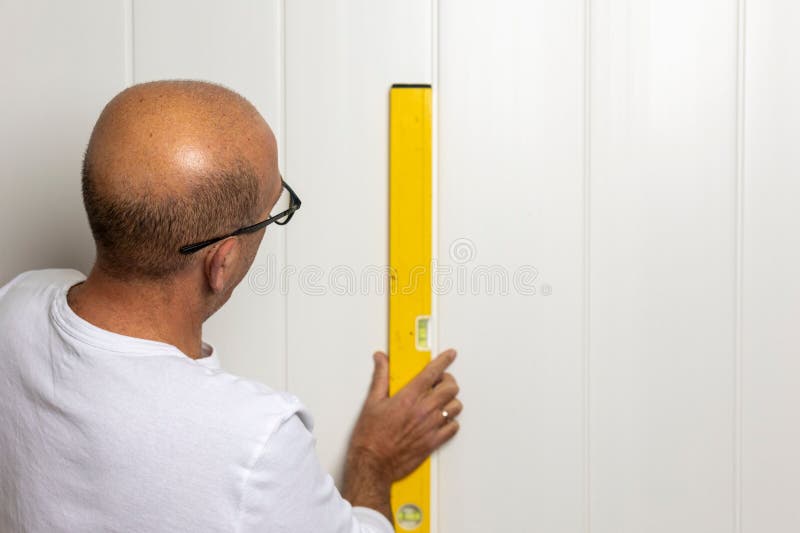 Male Construction Worker is Standing Near a Wall, Measuring the Length ...