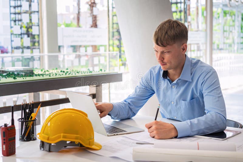 Male Construction Worker Working with Laptop and Blueprints at ...