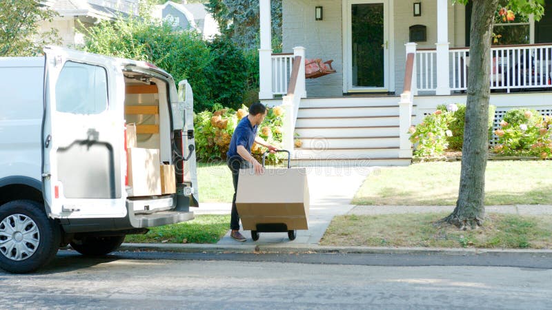Male Courier Using Trolley To Deliver Package from Van To House Stock ...