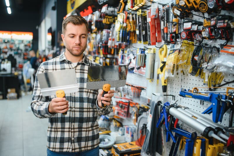 A Male Customer in a Modern Hardware Store Chooses Trowels Stock Photo ...