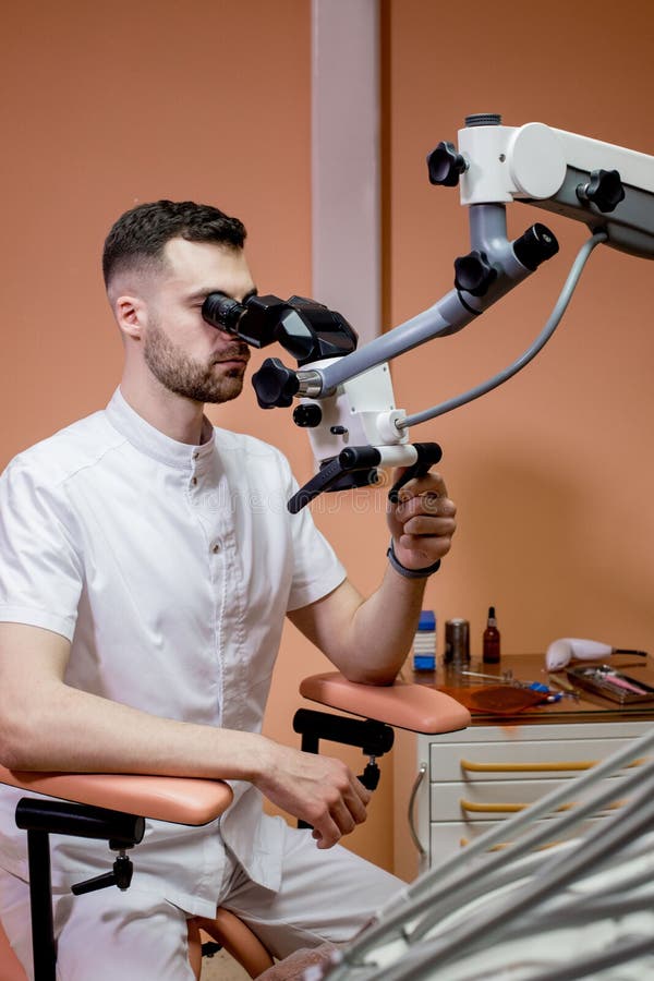 A Male Dentist Looks into a Microscope. Modern Dentistry Using New ...