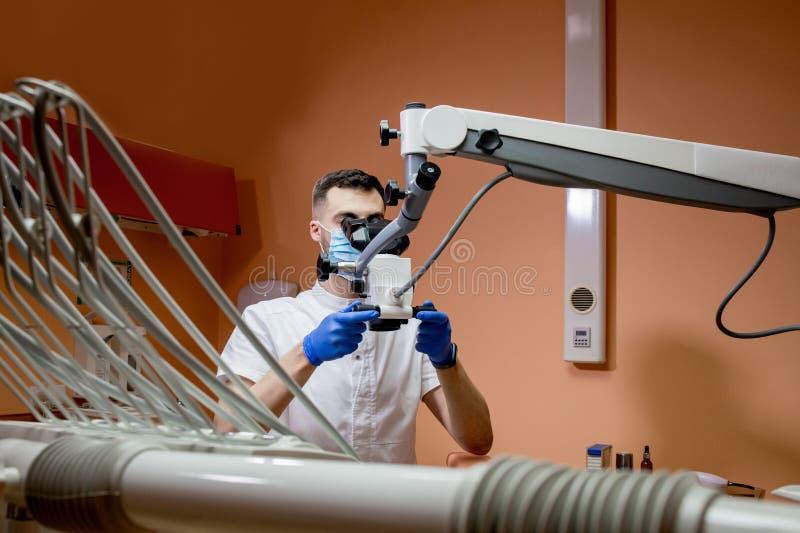 A Male Dentist Looks into a Microscope. Modern Dentistry Using New ...