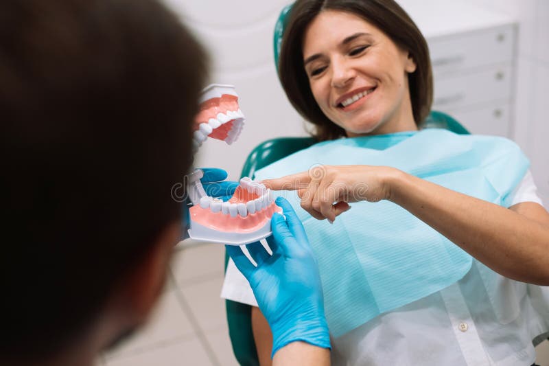 Male Dentist Shows Dentures with a Bracket in Her Hands To the Patient ...