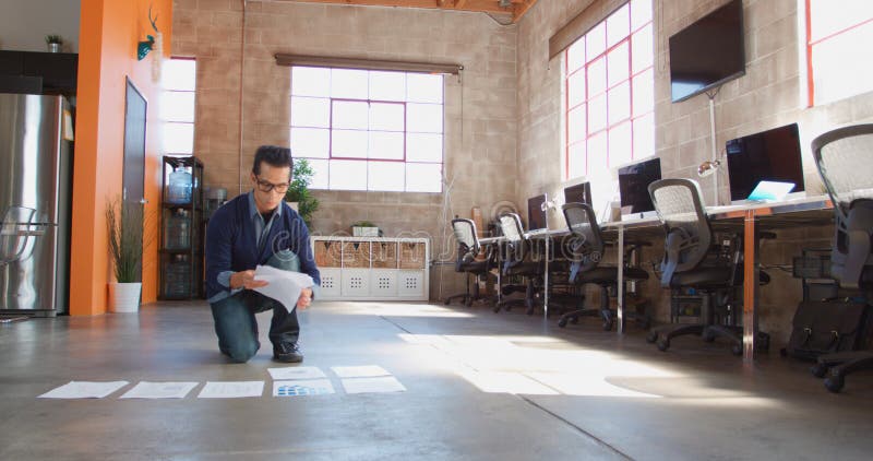 Male Designer Planning Campaign Laying Out Documents on Floor of Modern ...