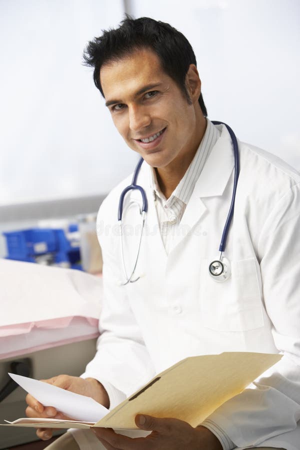 Male Doctor in Surgery Reading Patient Notes Stock Image - Image of ...