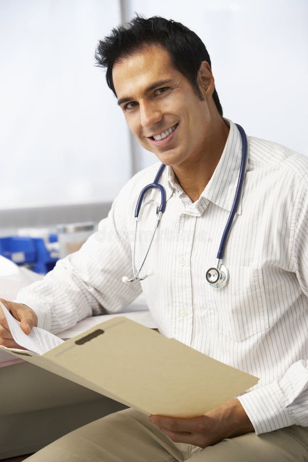 Male Doctor in Surgery Reading Patient Notes Stock Photo - Image of ...