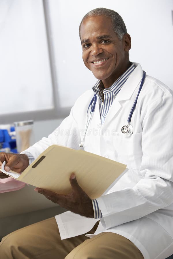 Male Doctor in Surgery Reading Patient Notes Stock Photo - Image of ...